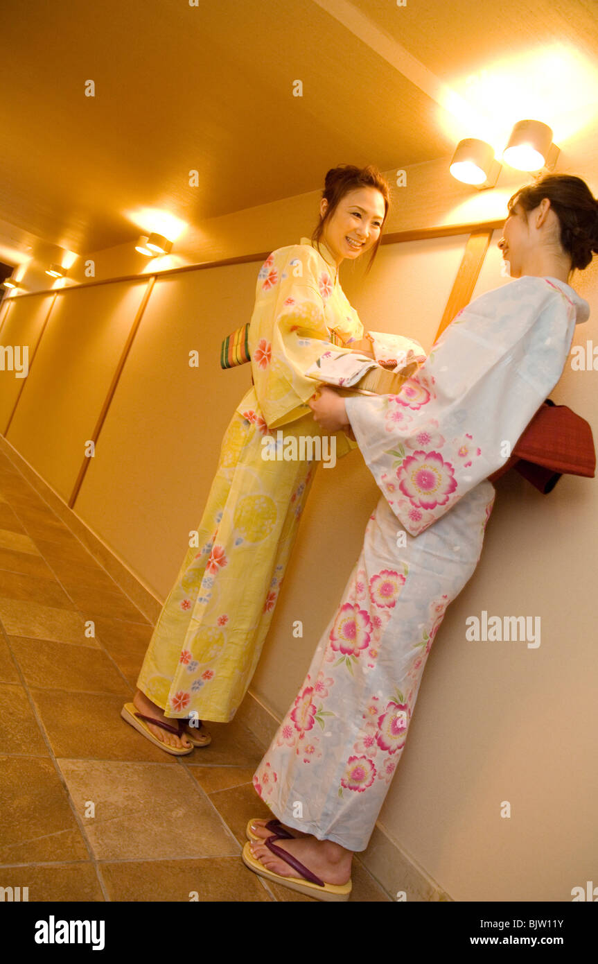 Women wearing yukata standing talking in hallway of health spa Stock ...