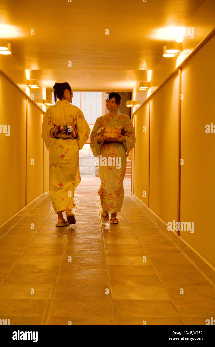 Two women wearing yukata passing each other in the corridor of a health ...
