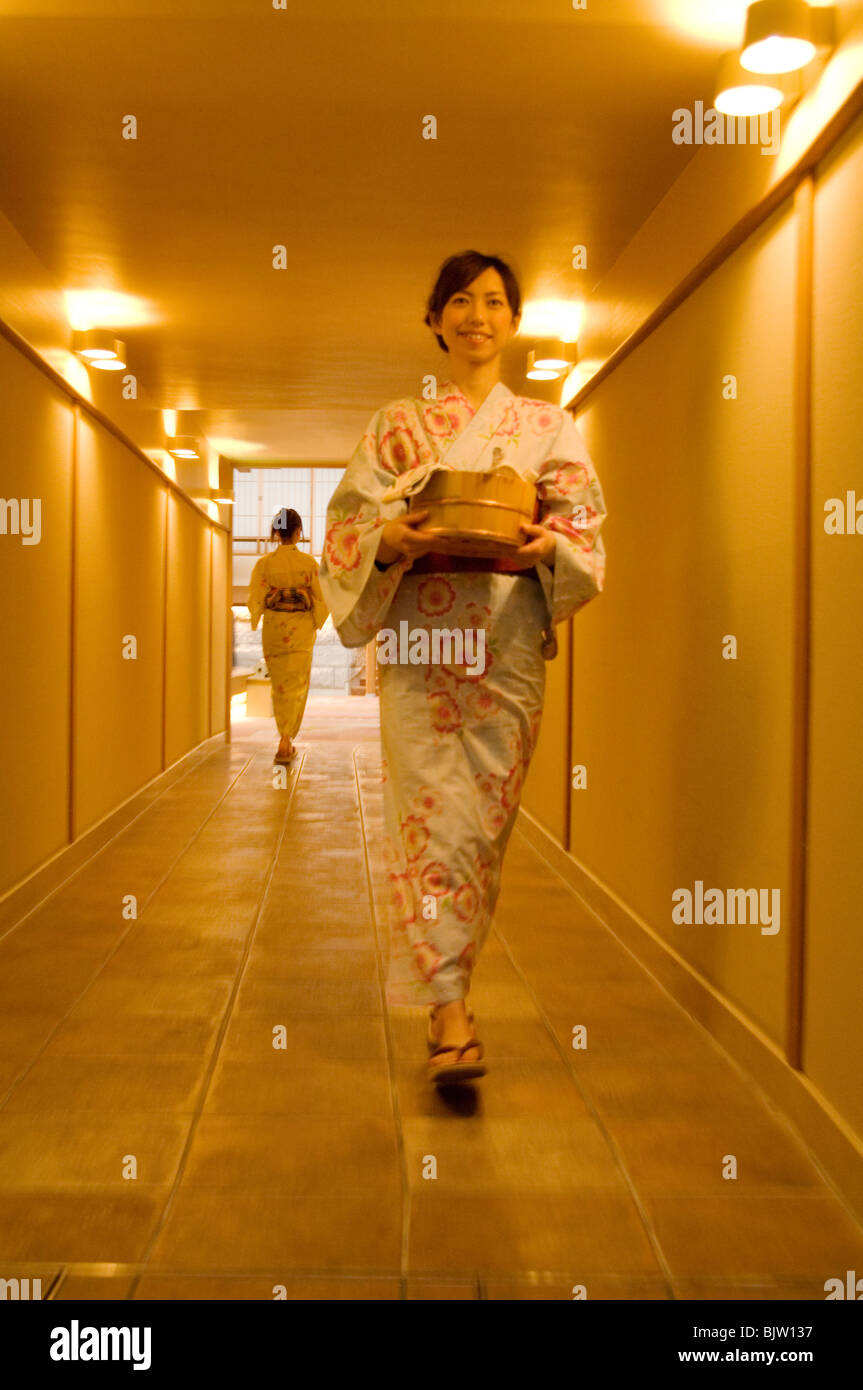 Two women wearing yukata walking through the corridor of a health spa ...