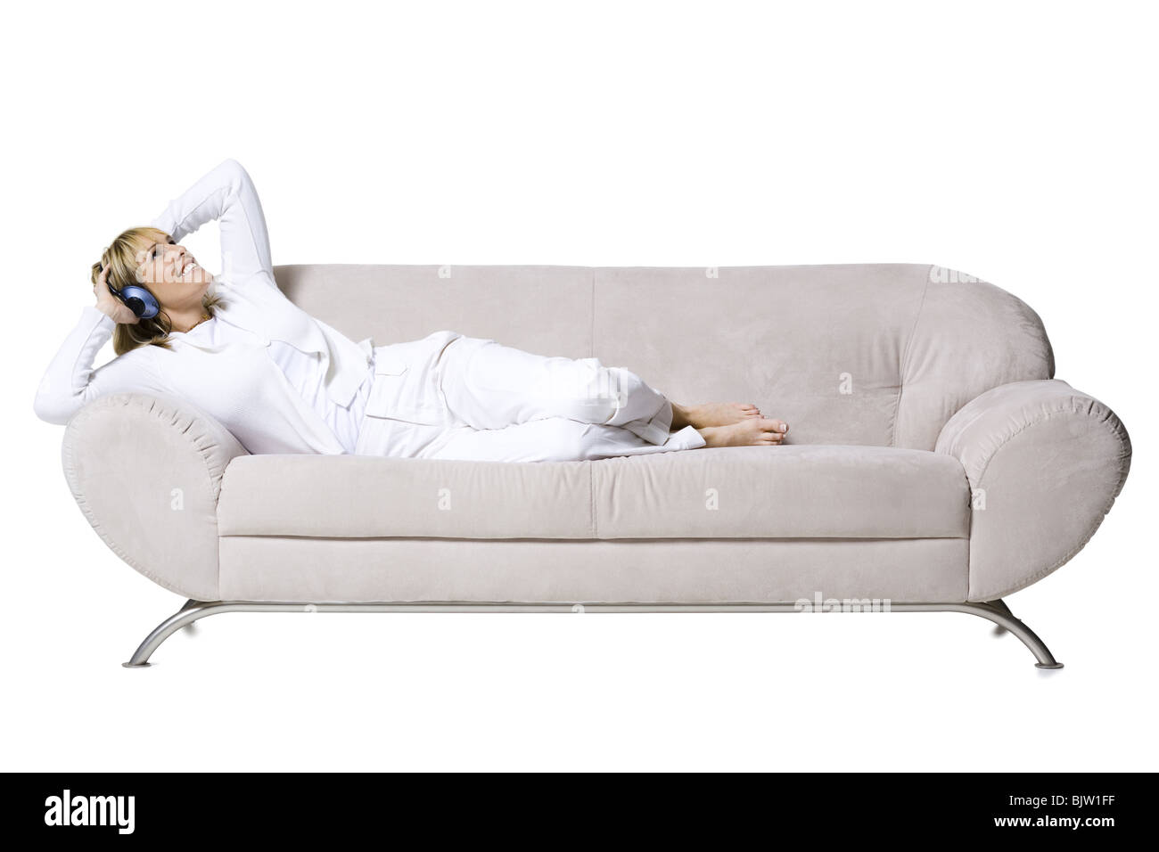 Woman smiling resting on couch with headphones Stock Photo - Alamy