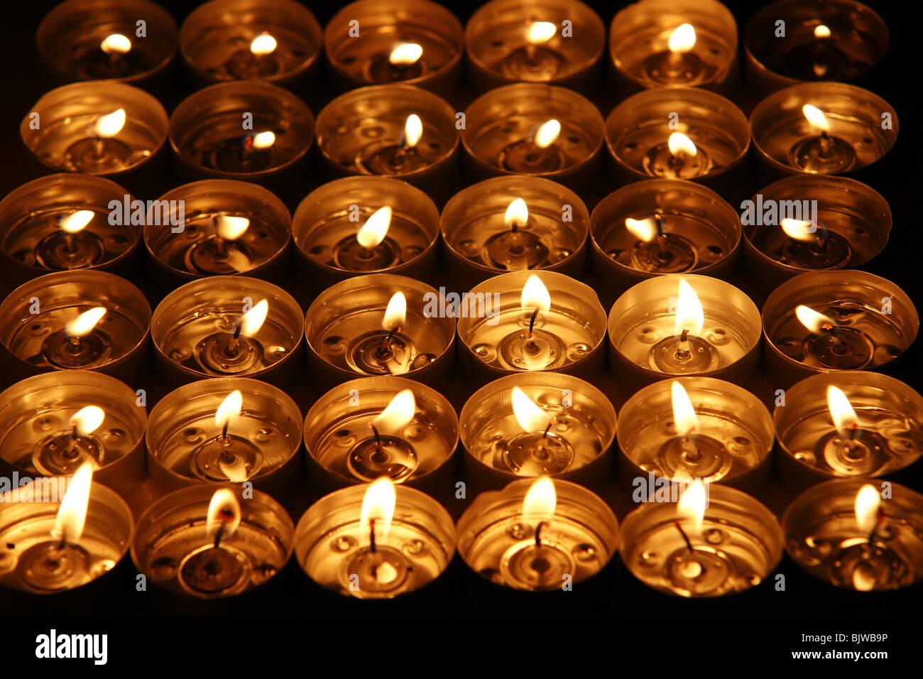 Many tealights candles lit at night flame detail Stock Photo - Alamy