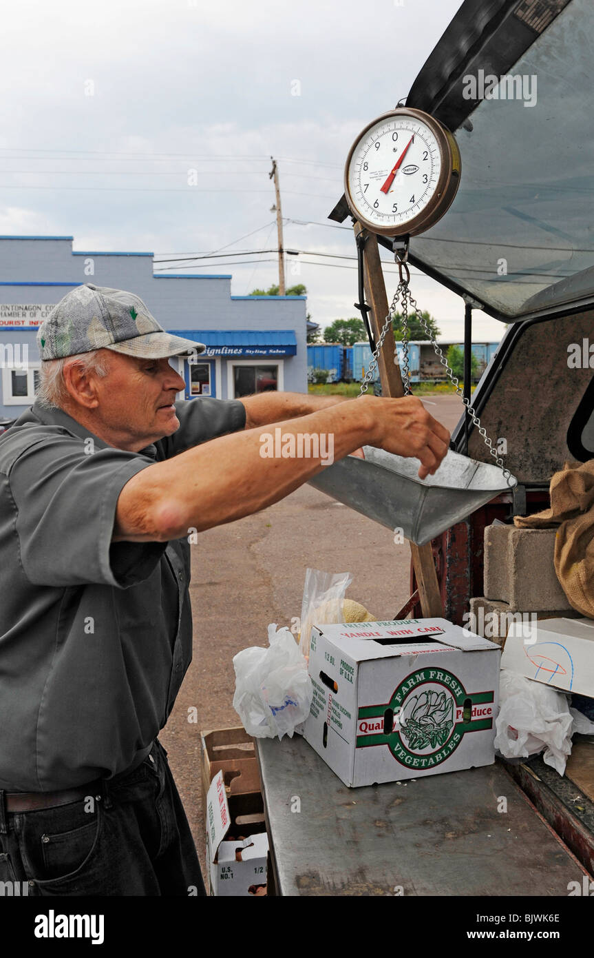 Vendor weighs product on scale at Roadside fruit and vegetable stand in ...