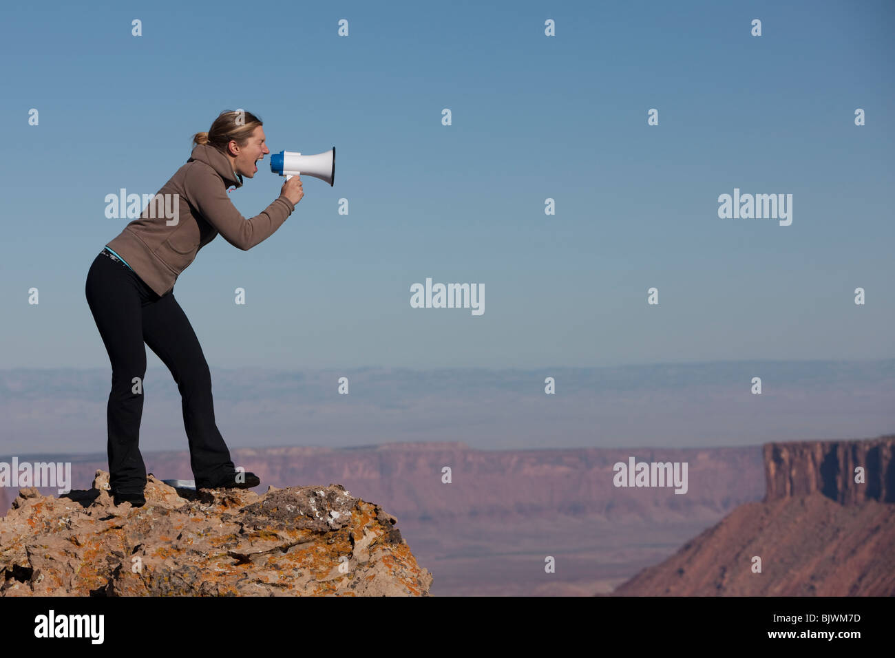 Woman yelling into megaphone at top of canyon Stock Photo - Alamy