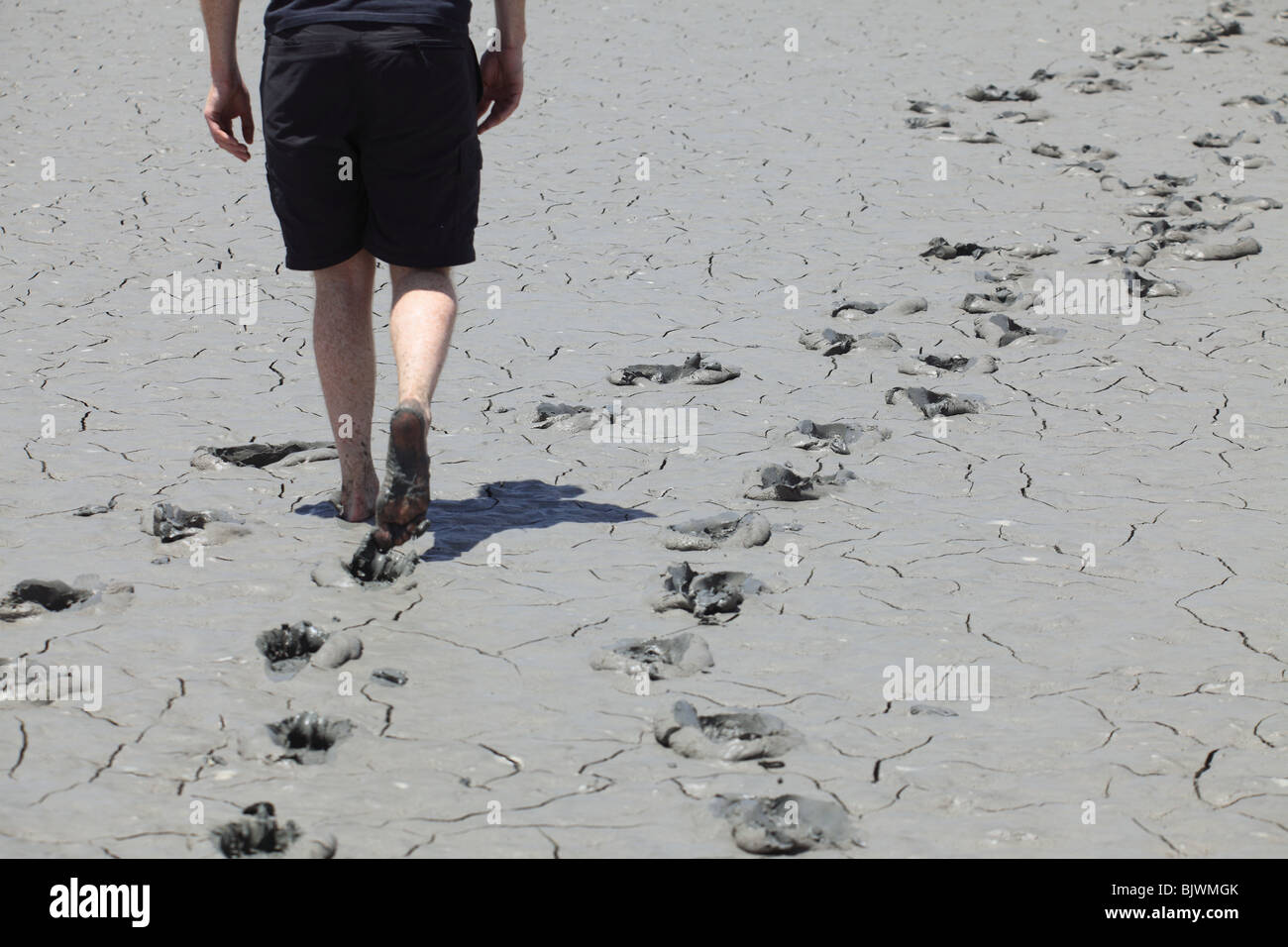 Person walking in a mud flat leaving deep footprints Stock Photo - Alamy