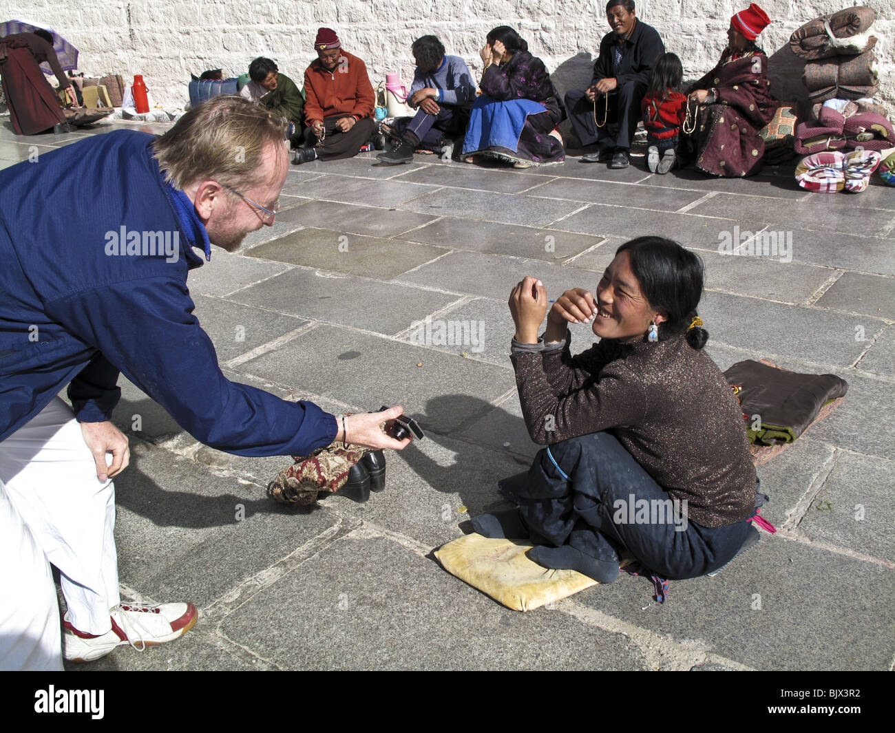 A tourist shows a photo taken to a Tibetan pilgrim in Barkor Square ...