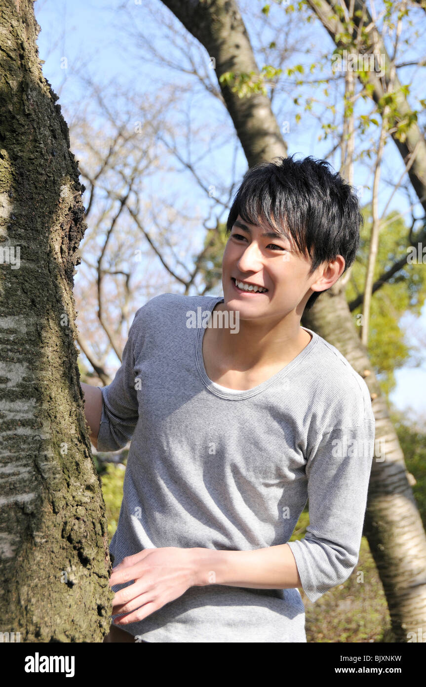 Young man hiding behind of tree Stock Photo - Alamy