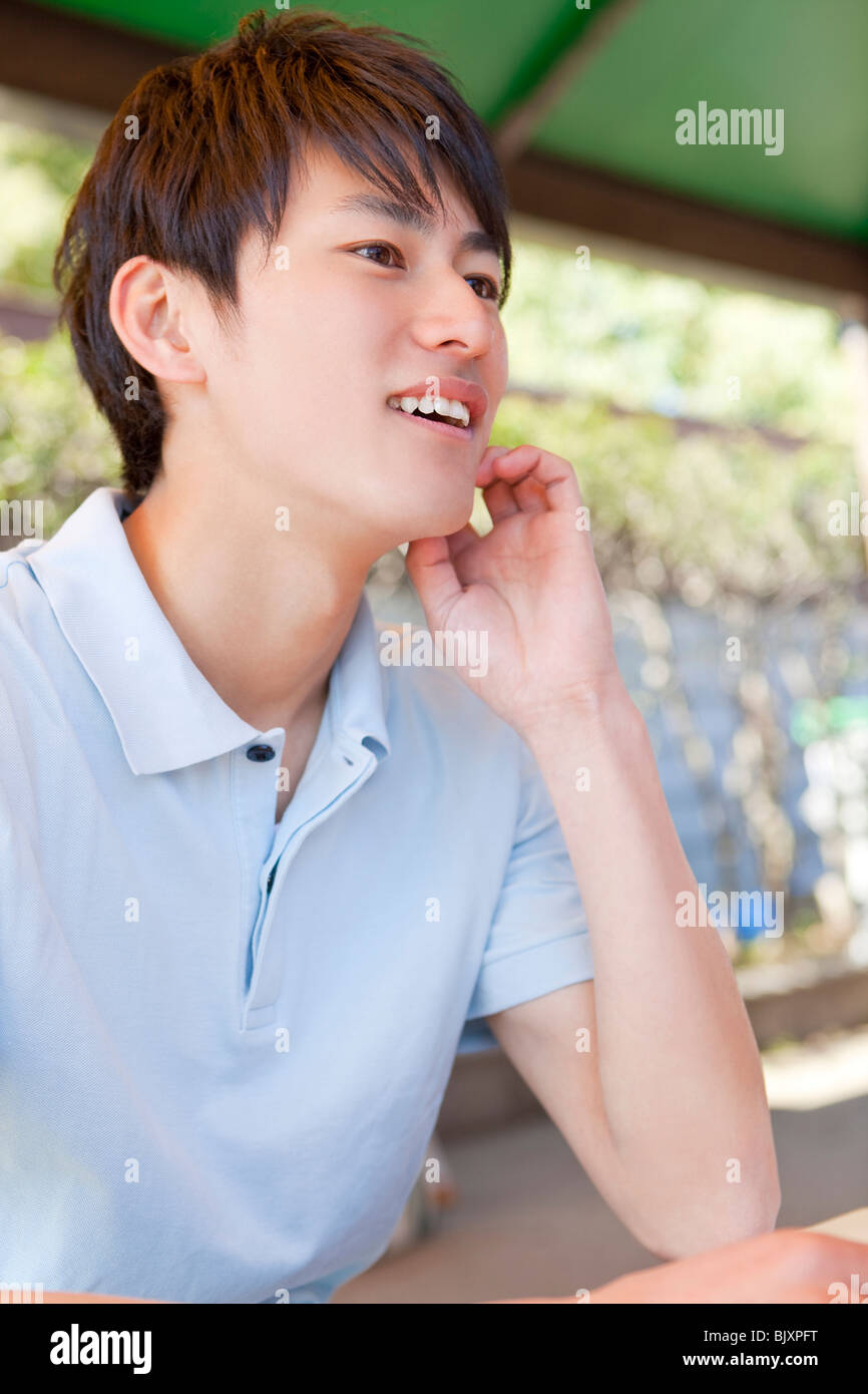 Portrait of young man with her hand on chin Stock Photo - Alamy