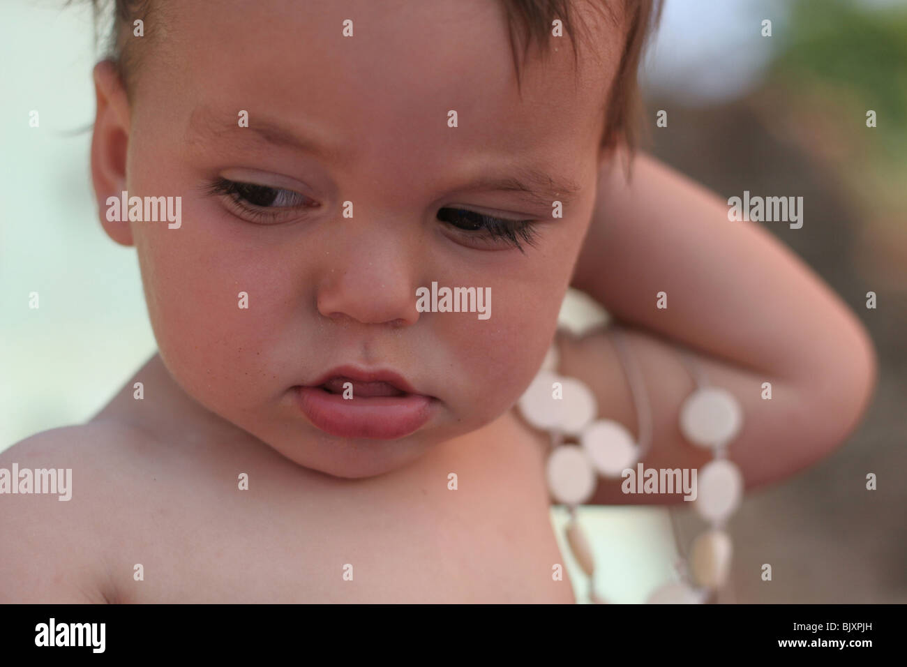 baby looking down to right hand corner holding string of beads, soft ...