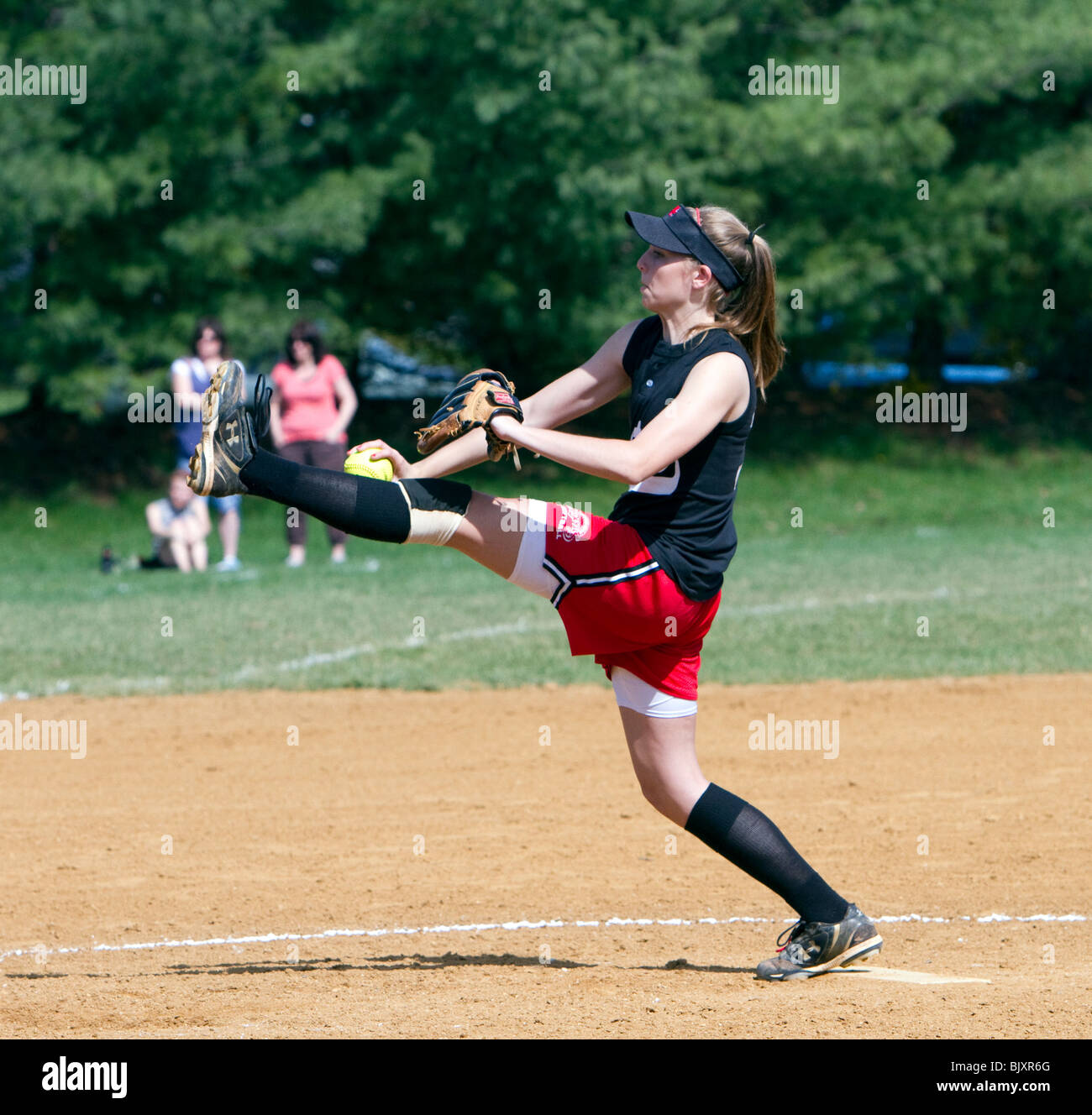 High kicking girls high school softball pitcher Stock Photo - Alamy