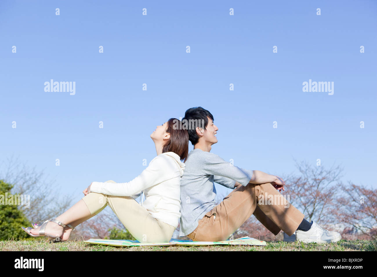 Young couple sitting back to back Stock Photo - Alamy