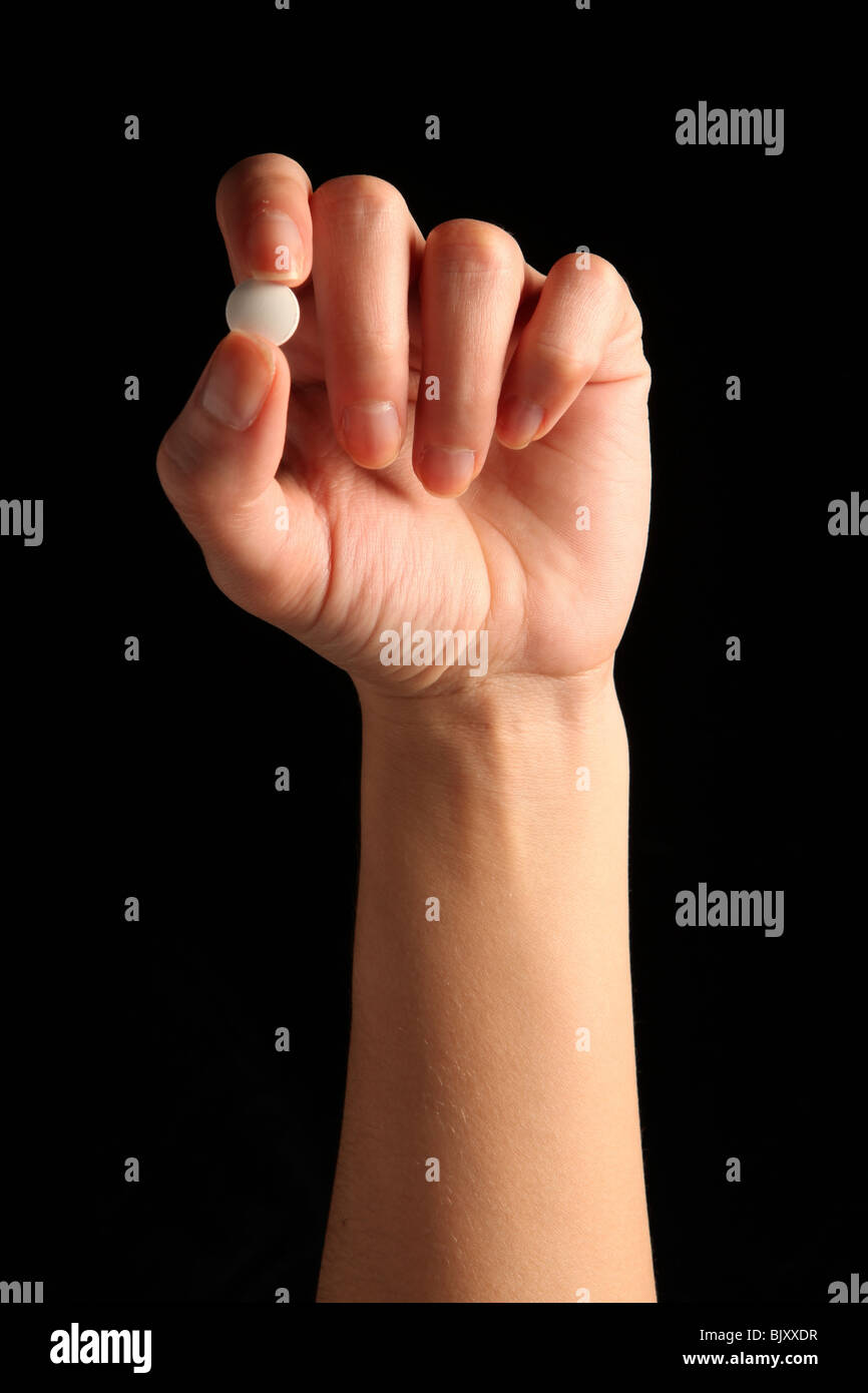 A female hand holding a small white pill between fingers Stock Photo ...