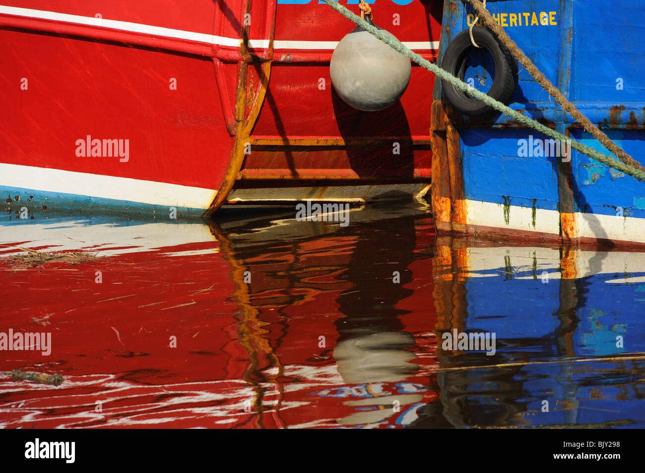 Bright red and blue reflections of fishing boat hulls Kirkcudbright ...