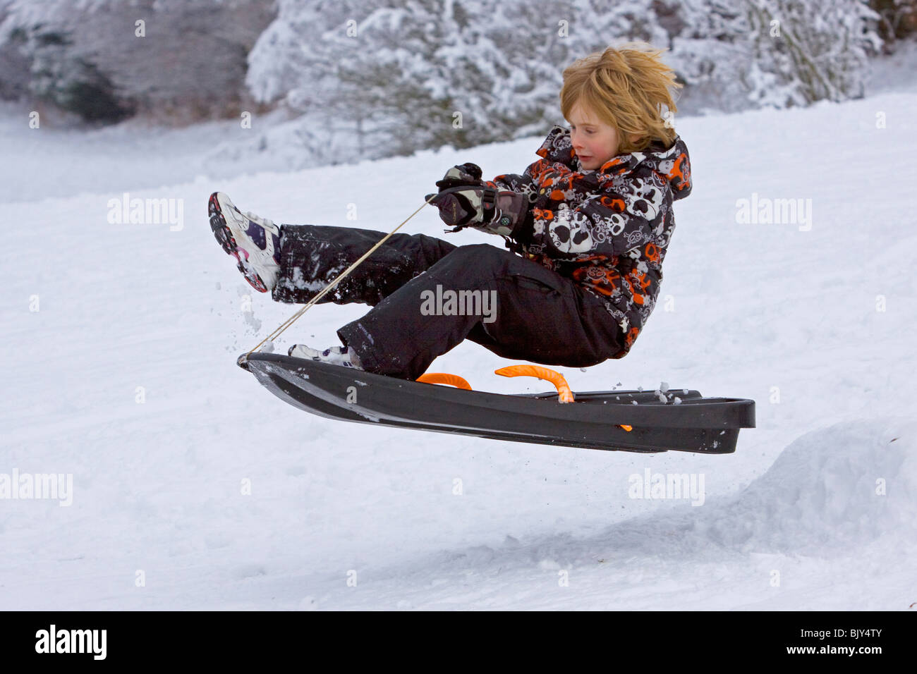 Sledging child playing snow winter play toboggan tobogganing Stock ...