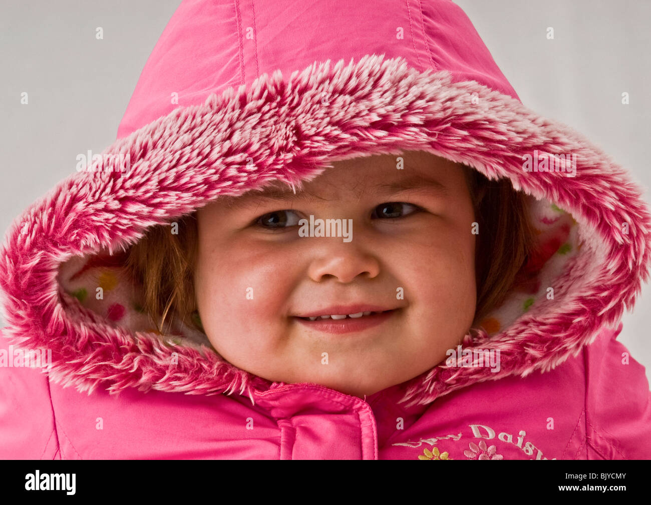 Close-up of a cute little girl wearing red winters parka jacket with ...