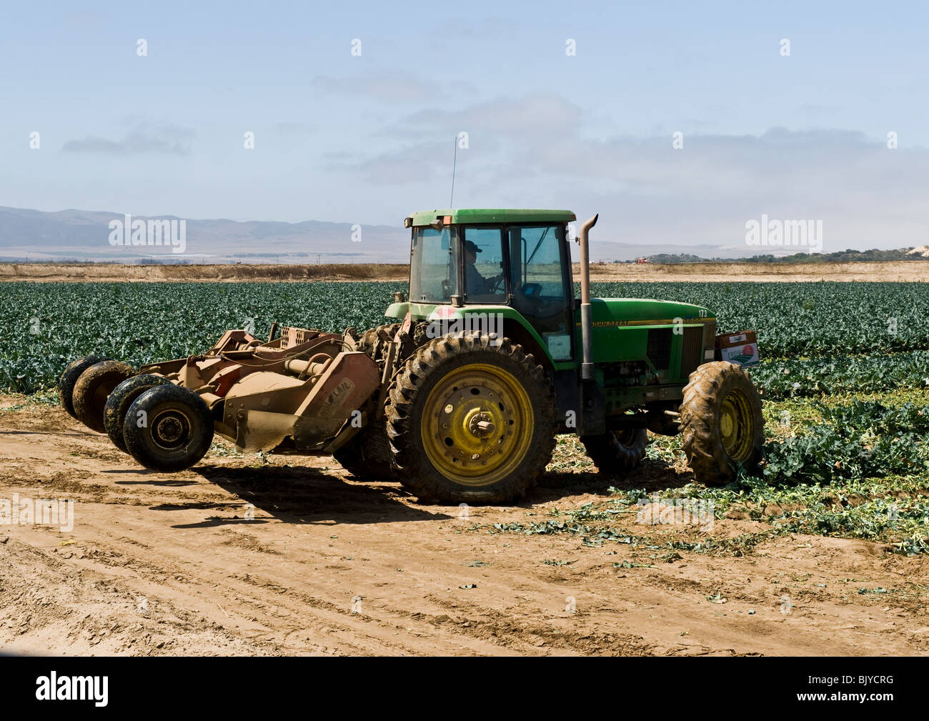 Farmer in tractor with agriculture machinery harvesting and ploughing ...