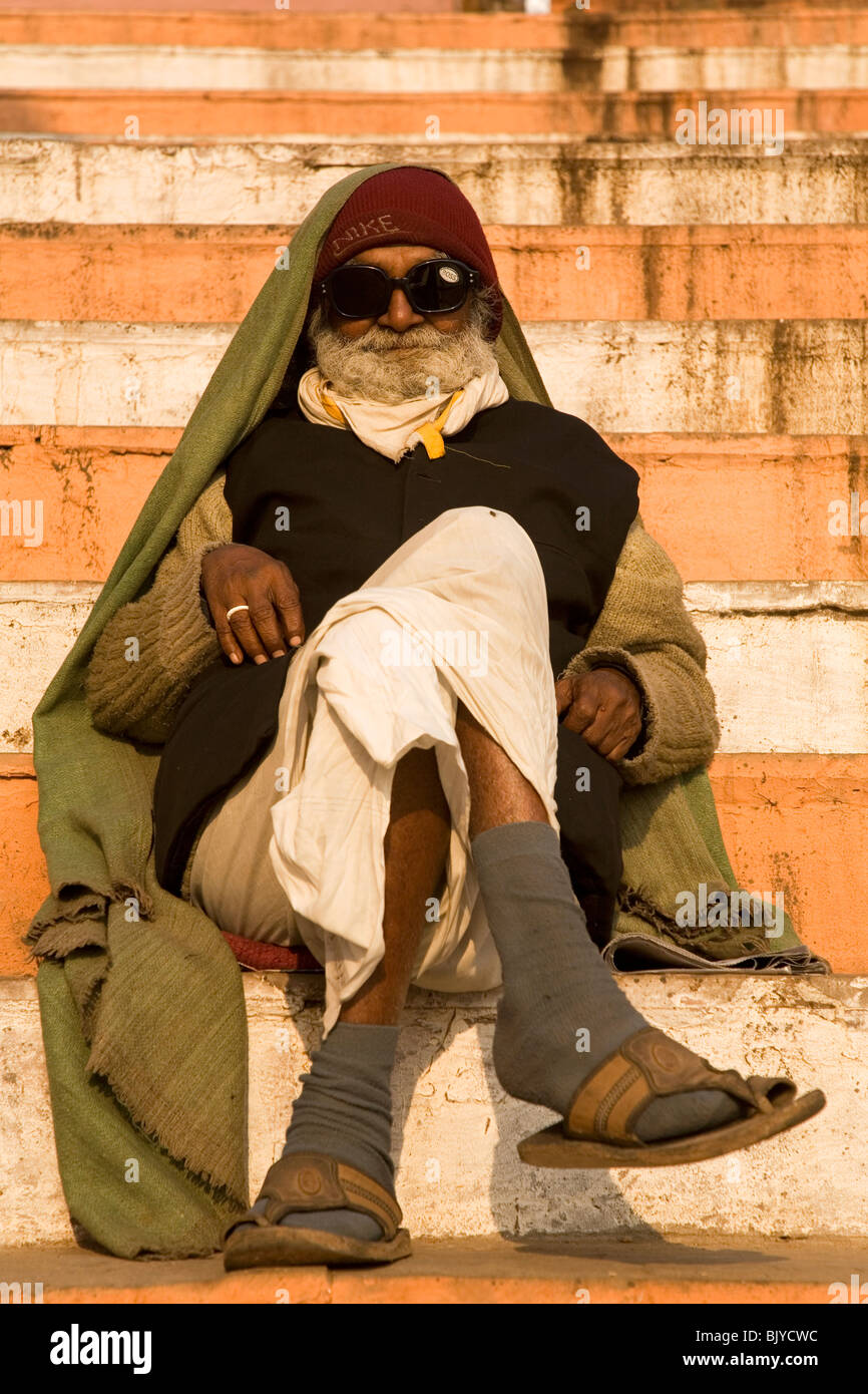An Indian man wears a woolly hat and sun glasses on the ghats in ...