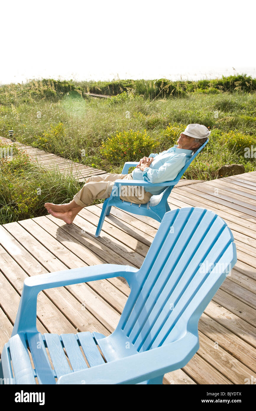 Senior man sitting on chair snoozing in the sun on wood deck Stock ...
