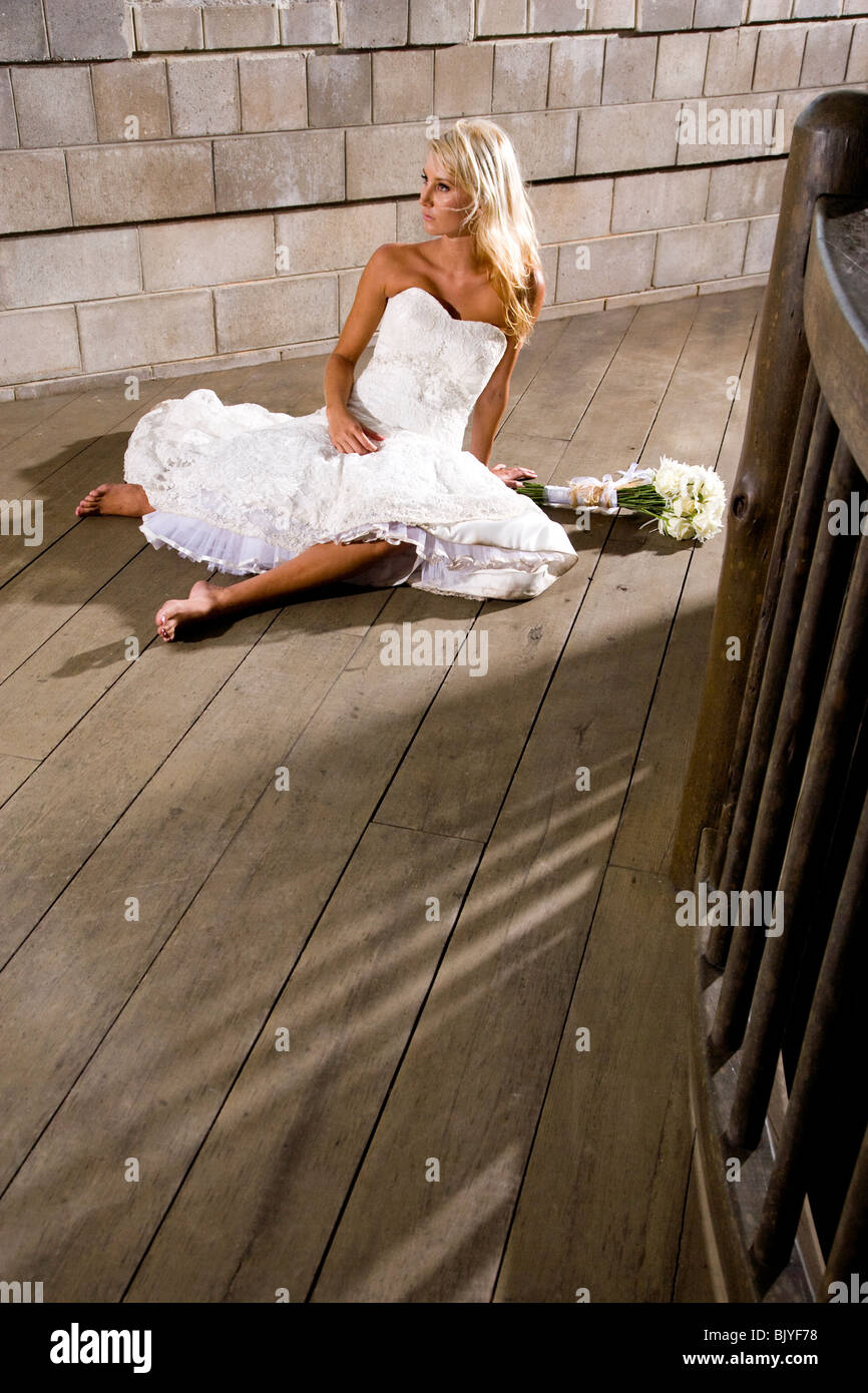Young woman in white dress sitting barefoot on floor with bouquet Stock ...