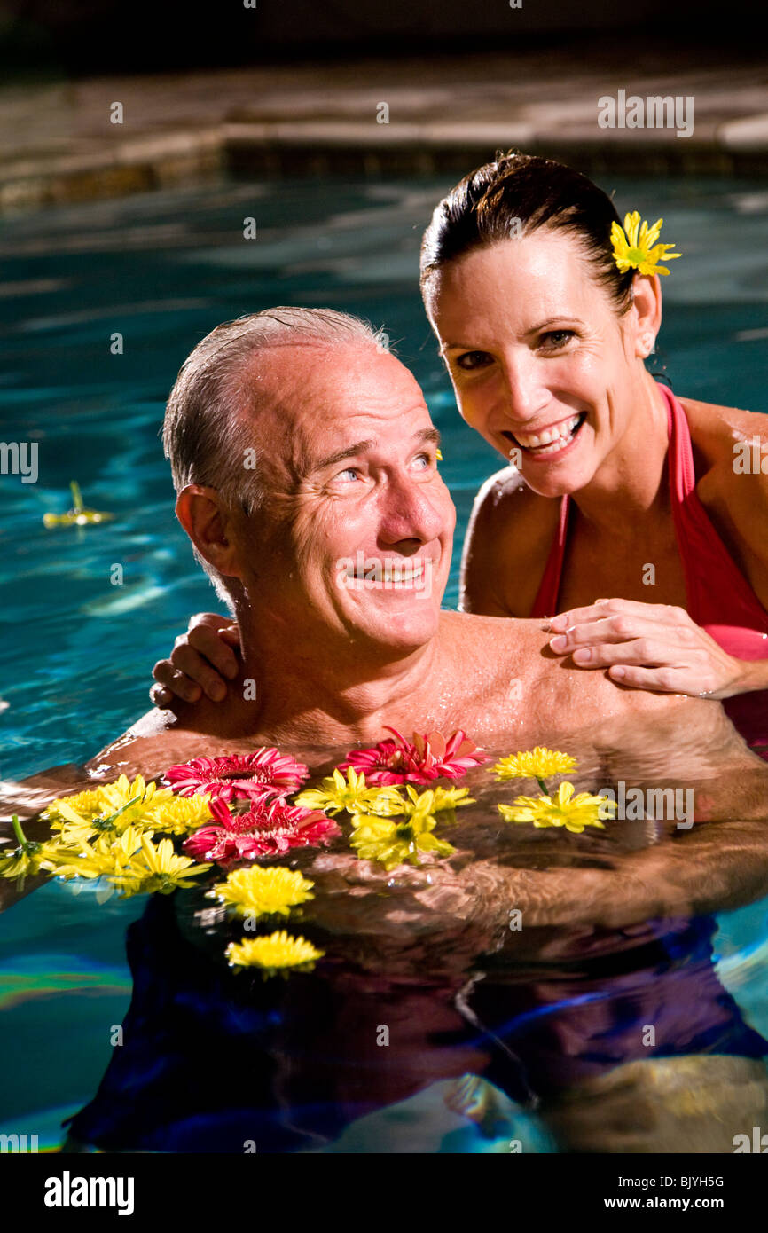Romantic couple in swimming pool surrounded by floating flowers Stock ...