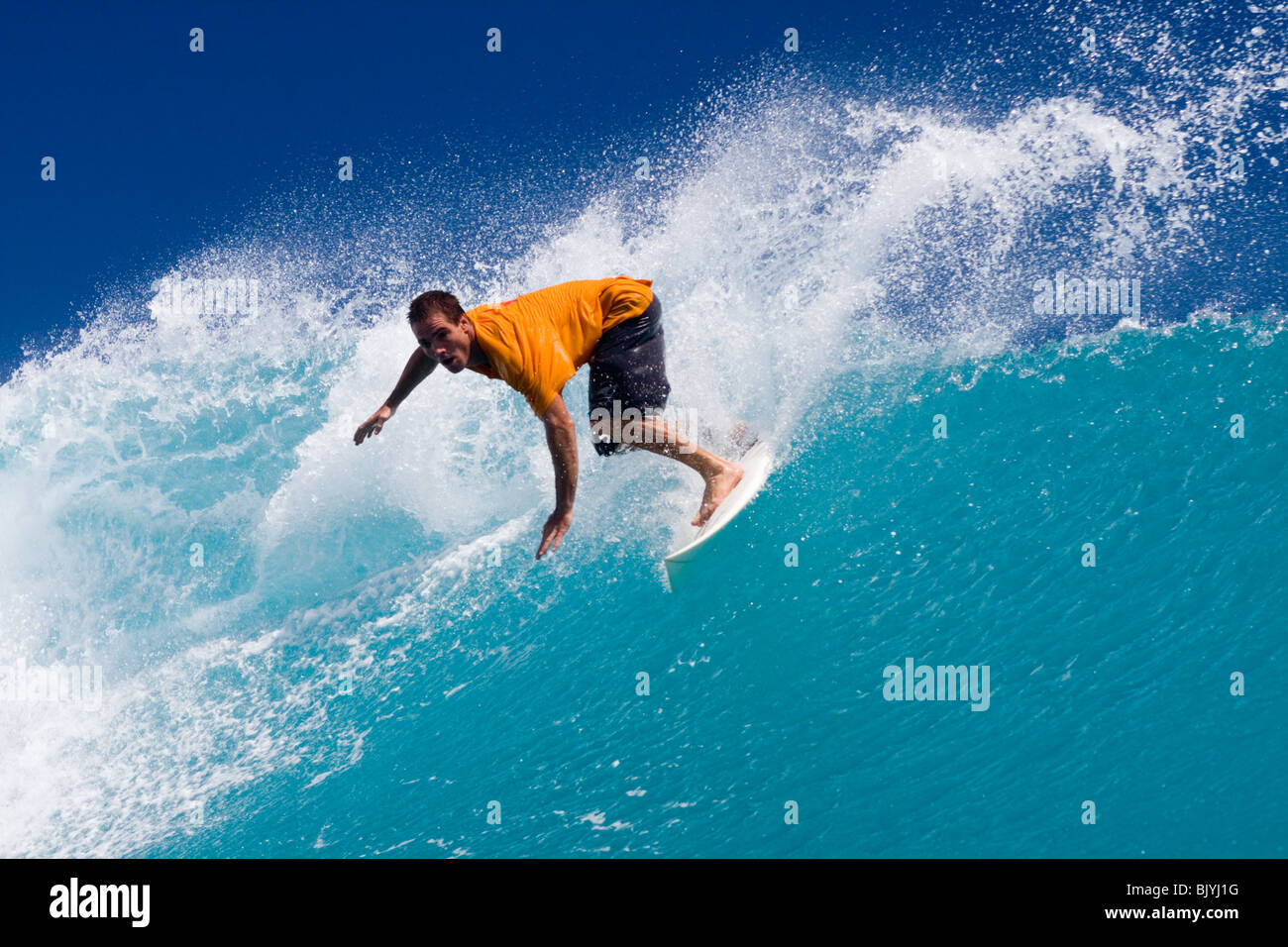 A surfer turns off the top of a blue wave in Maui Stock Photo - Alamy