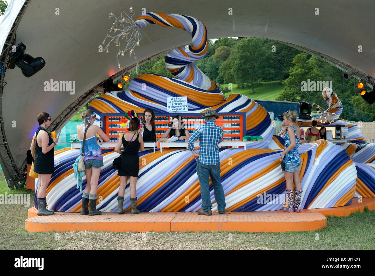 Festival goers buy cigarettes at brightly coloured shop Stock Photo - Alamy
