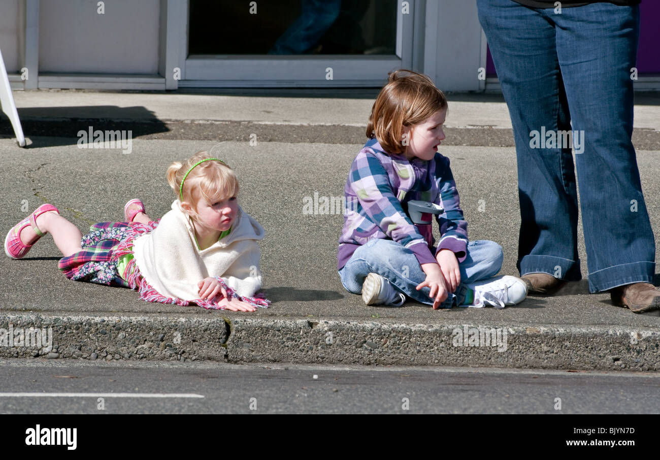 These two cute little girls are awaiting a parade to start. One child ...