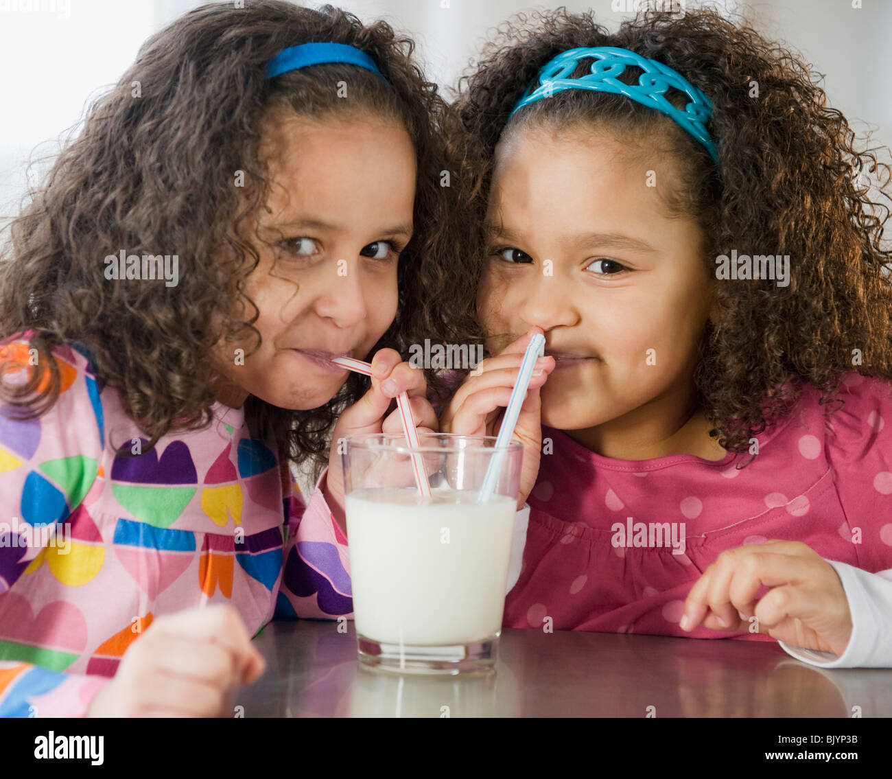 Hispanic sisters sharing glass of milk Stock Photo - Alamy