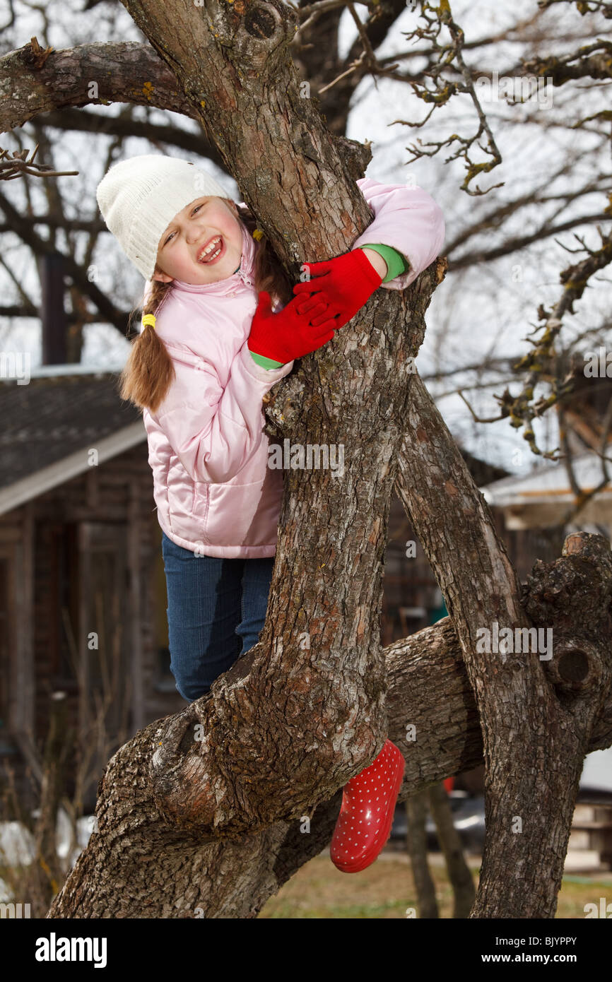 Little girl sitting in a tree in garden Stock Photo - Alamy