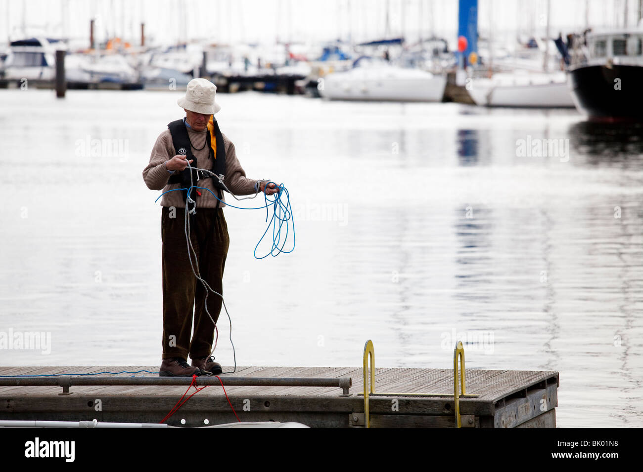 senior leisure sailor yachtsman sorting ropes / sheets whilst standing ...
