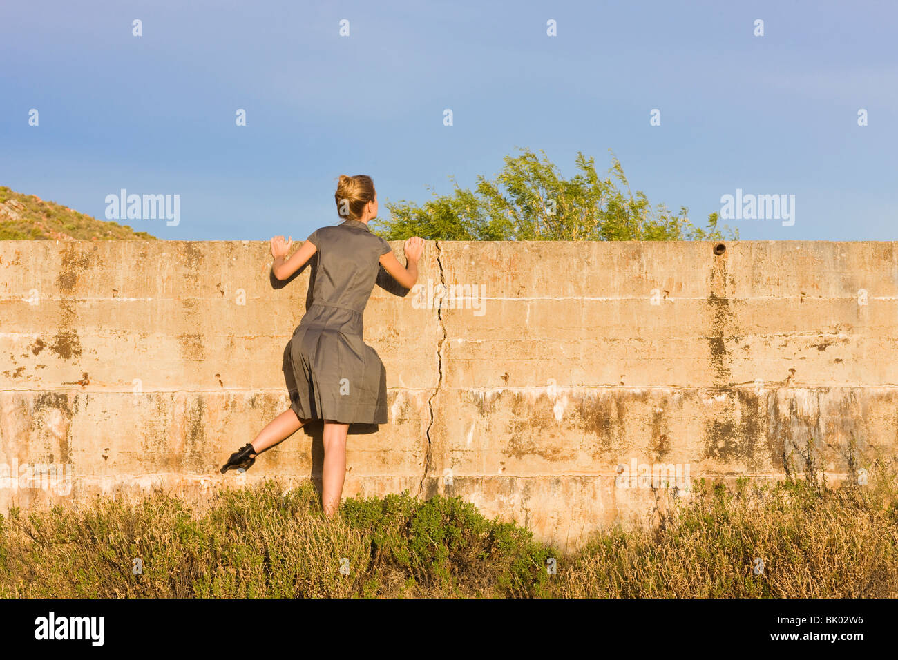 Woman looking over wall Stock Photo - Alamy