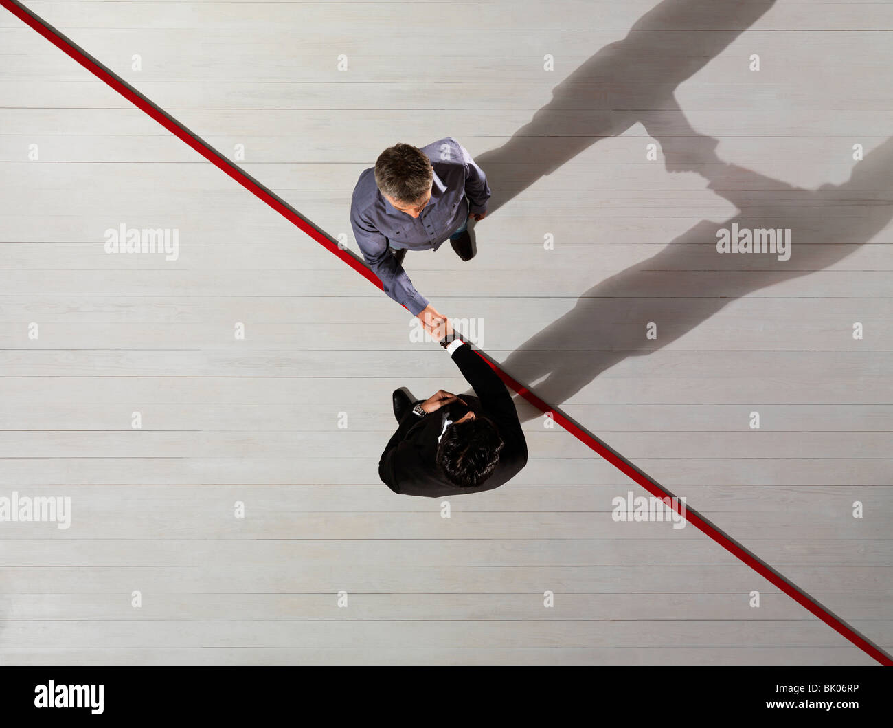 Business men Shaking hands over red line Stock Photo - Alamy