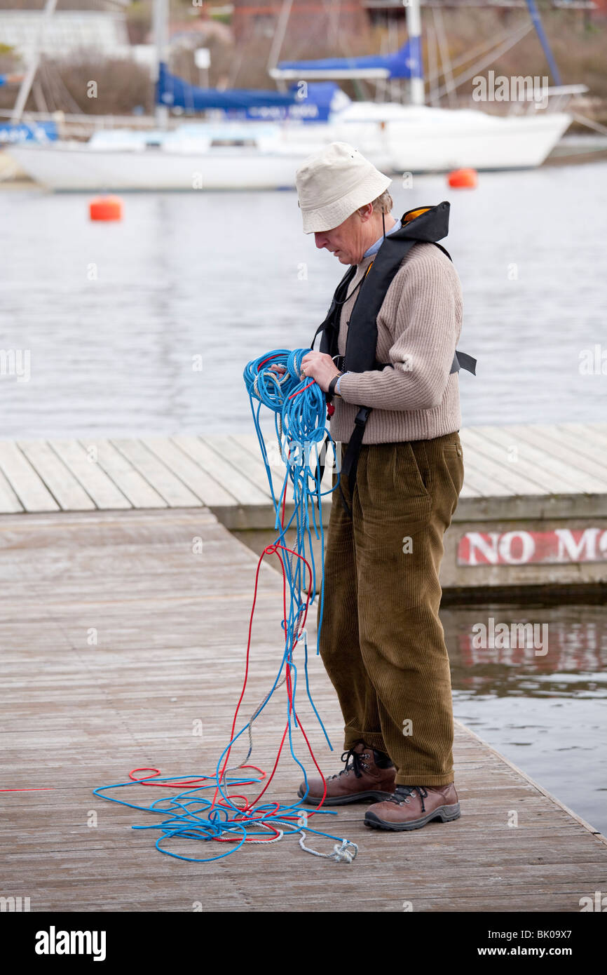 senior leisure sailor yachtsman sorting ropes / sheets whilst standing ...