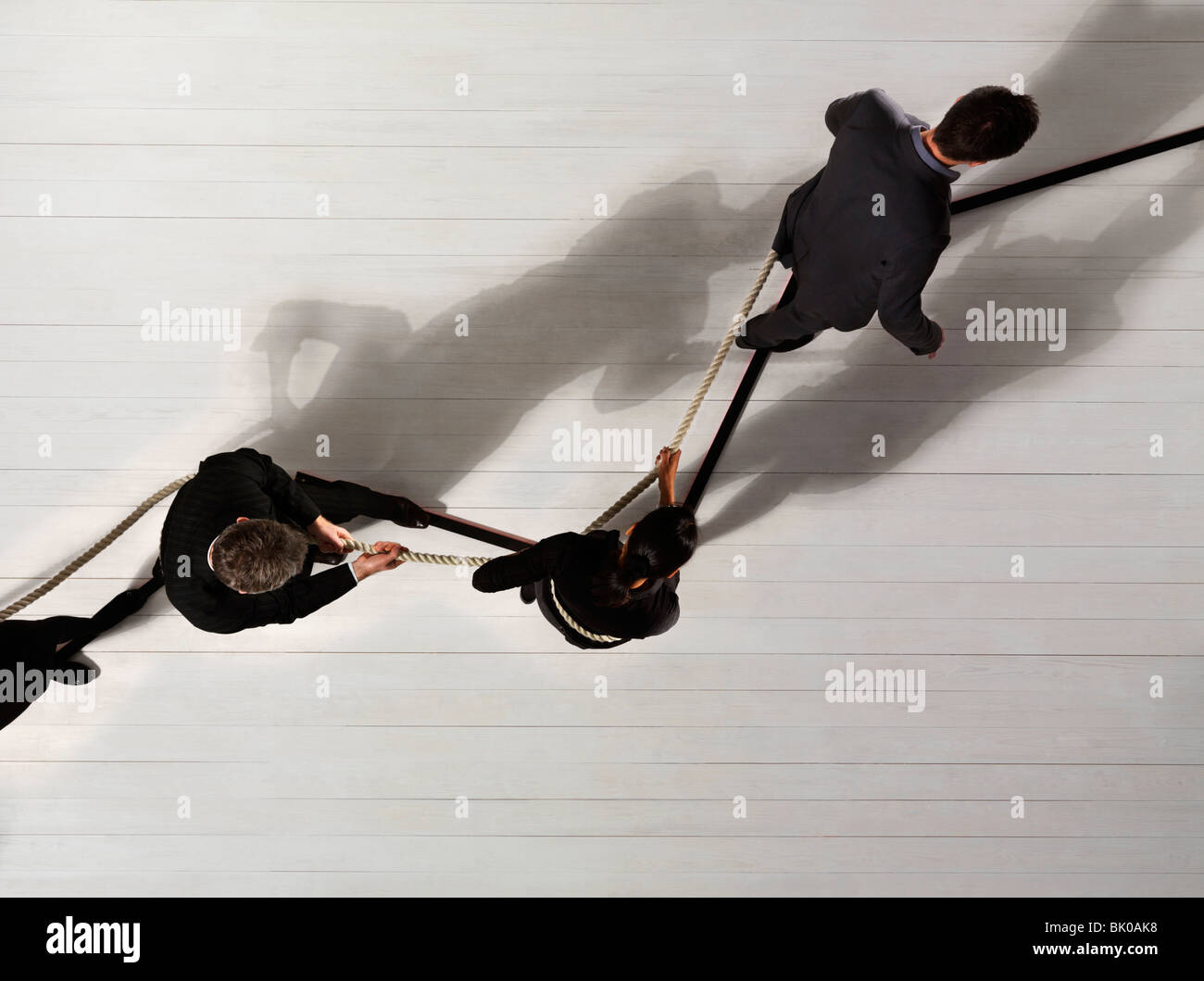 Business man leading others with rope Stock Photo - Alamy