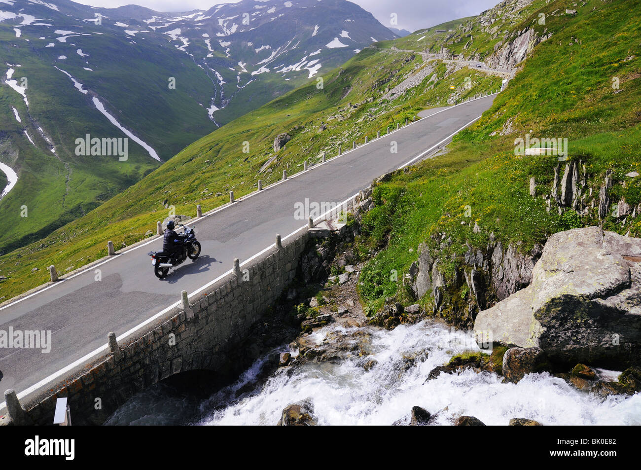 Perspective of Alpine road with biker Stock Photo - Alamy