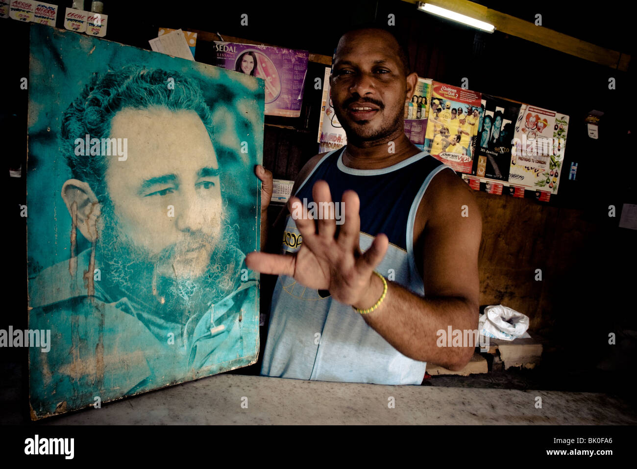 A Cuban shop assistant holds a large portrait photo of the Cuban ...