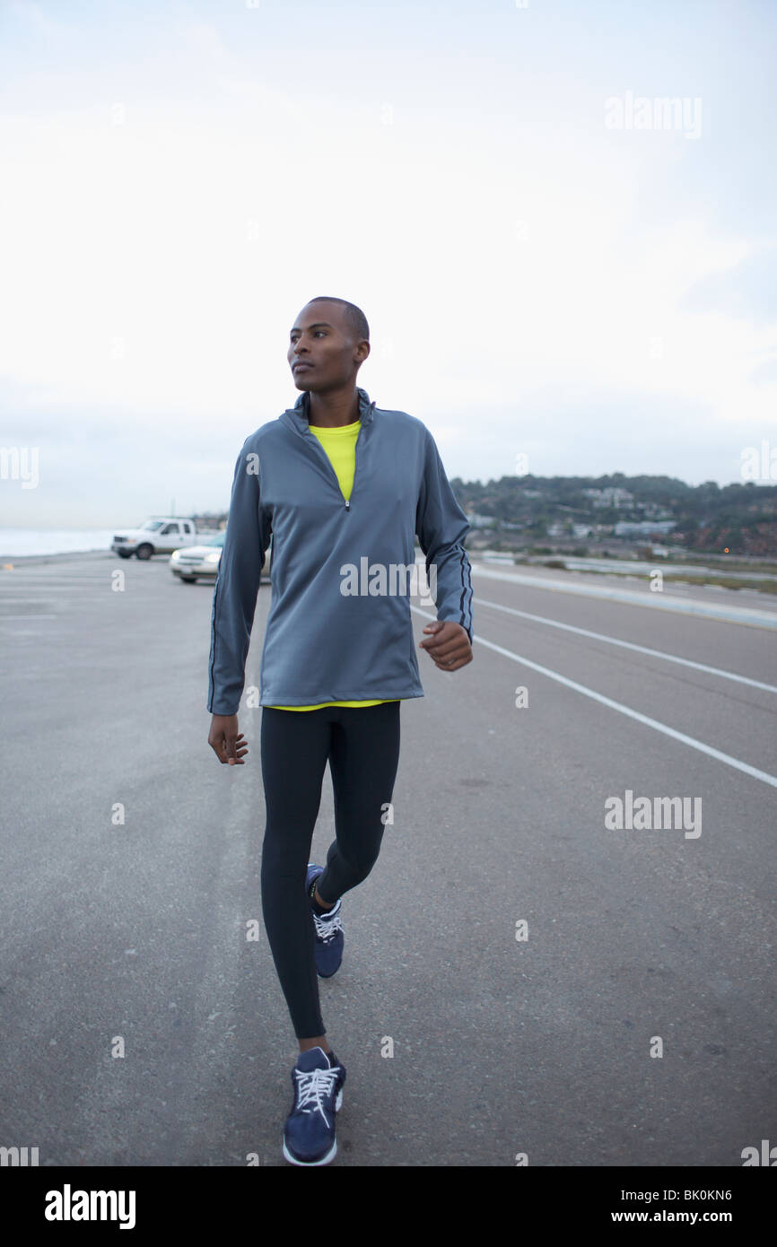 Athletic Black man walking along road Stock Photo - Alamy