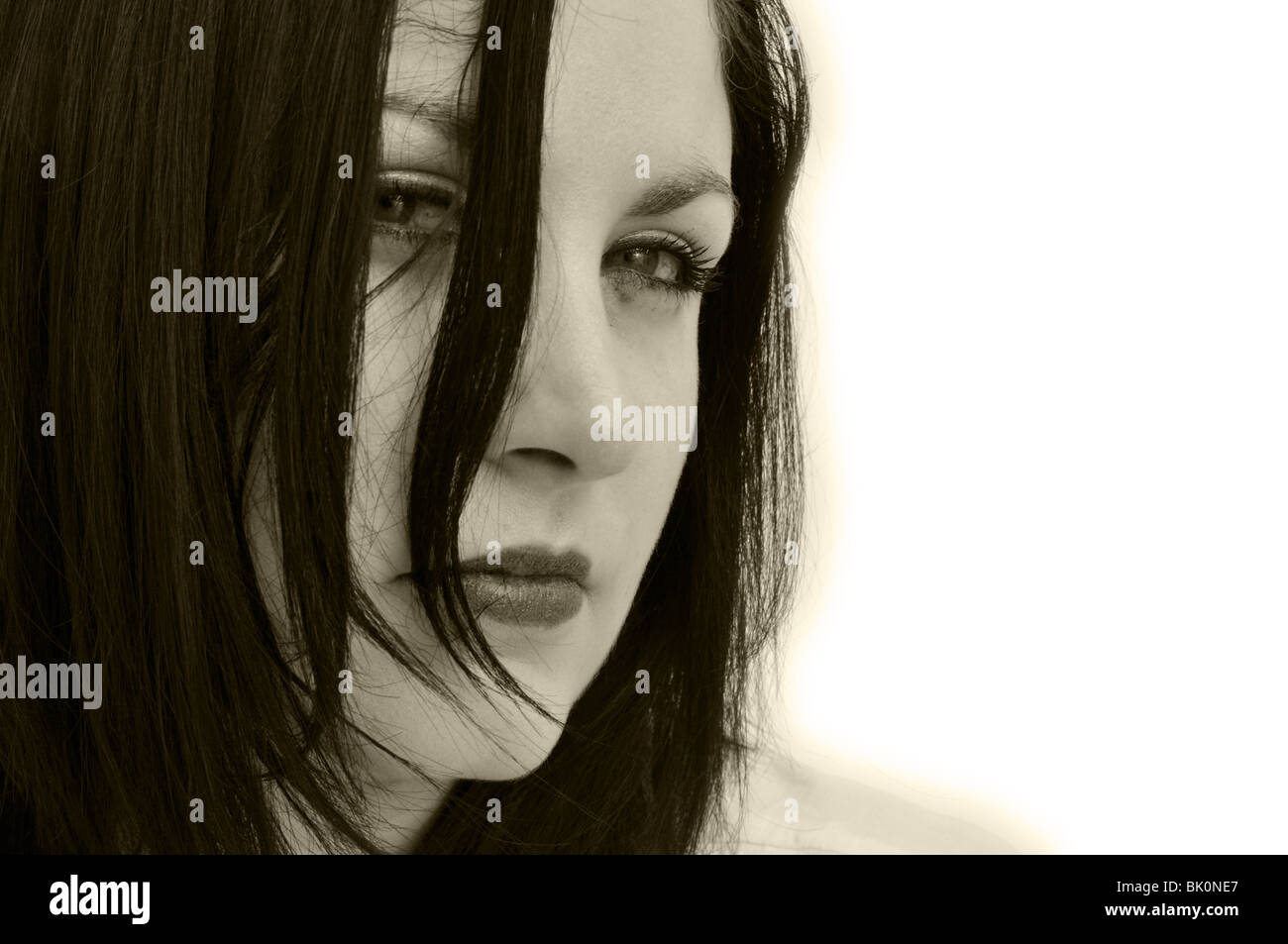 close up studio portrait of young woman with black hair falling over ...
