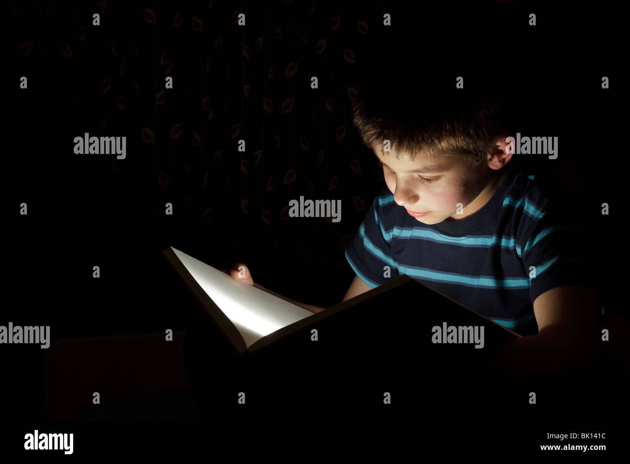 Boy reading bedtime story, dark photo, key light coming from book Stock ...
