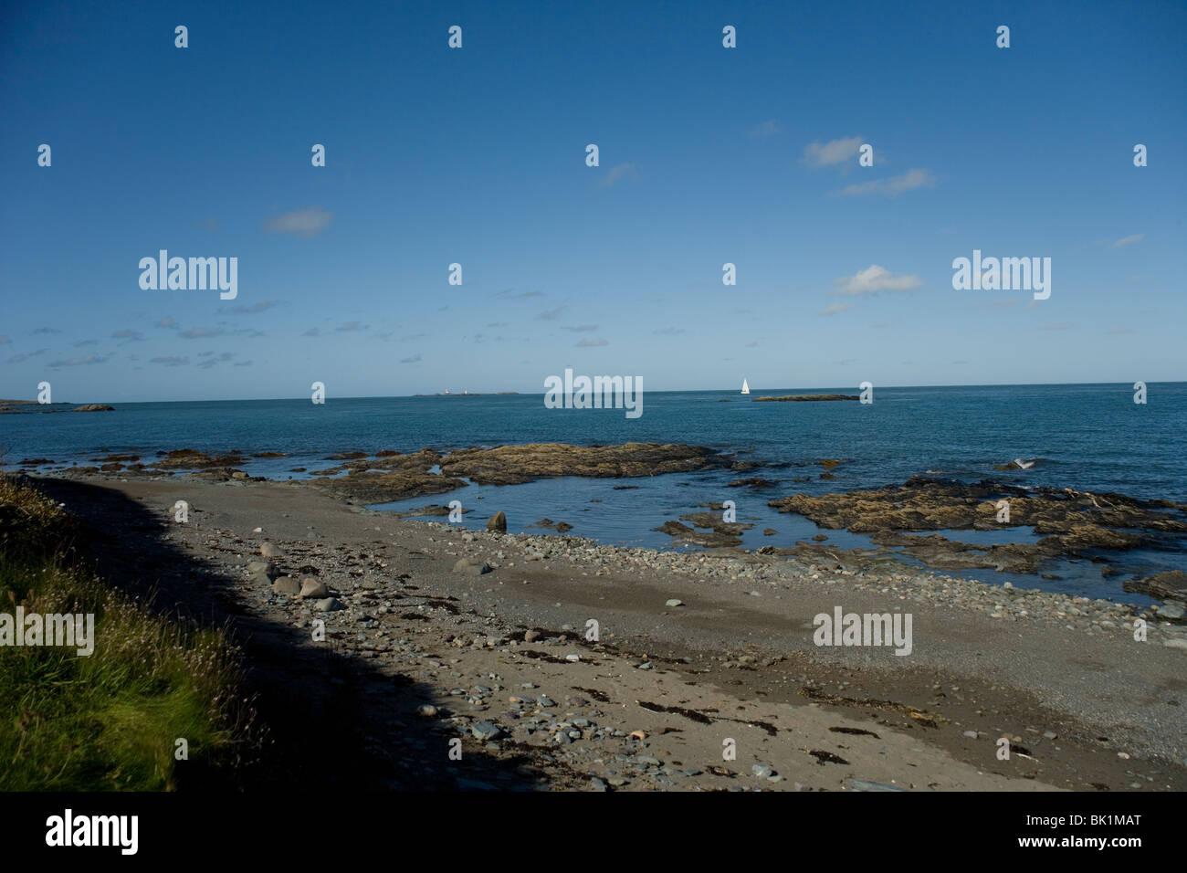 Skerries Lighthouse and yacht from the Anglesey coastal footpath Stock ...