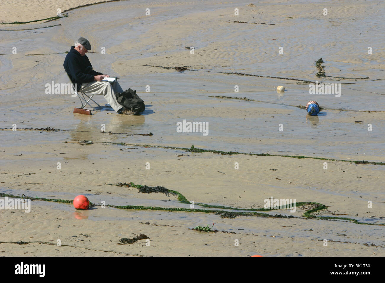 Man sitting on the sand in St Ives harbour at low tide, Cornwall Stock ...