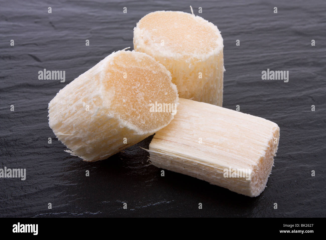 Chunks of Raw Sugar Cane against dark slate background Stock Photo - Alamy