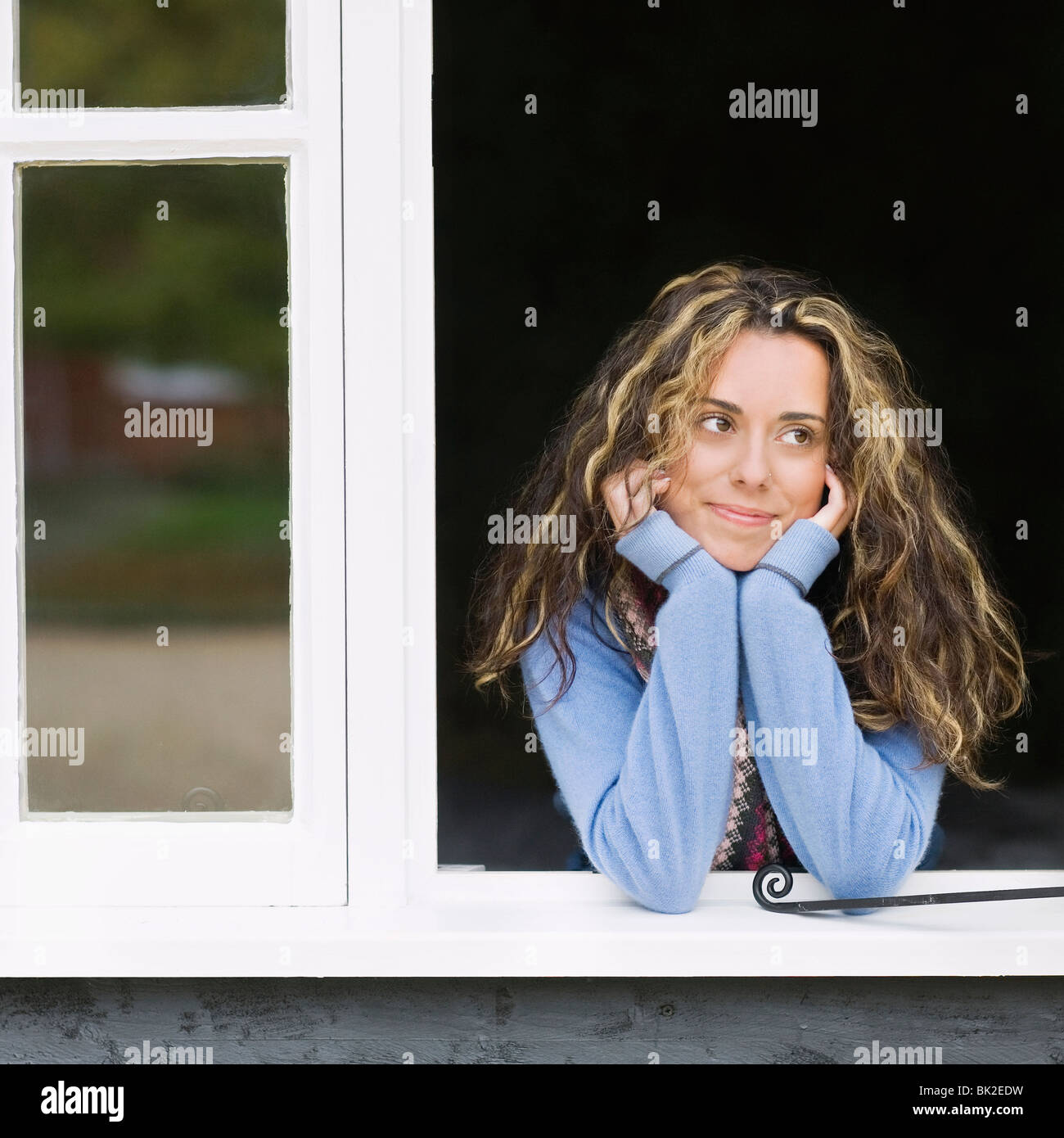 Smiling woman looking out window Stock Photo - Alamy