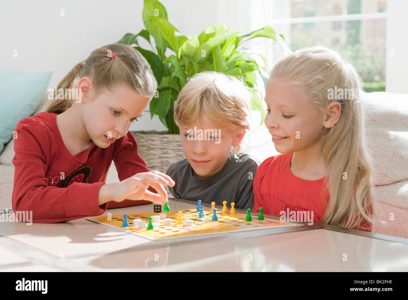 Three children playing a board game Stock Photo - Alamy