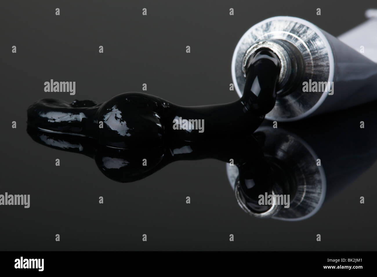 black paint flowing from tube onto black surface Stock Photo - Alamy