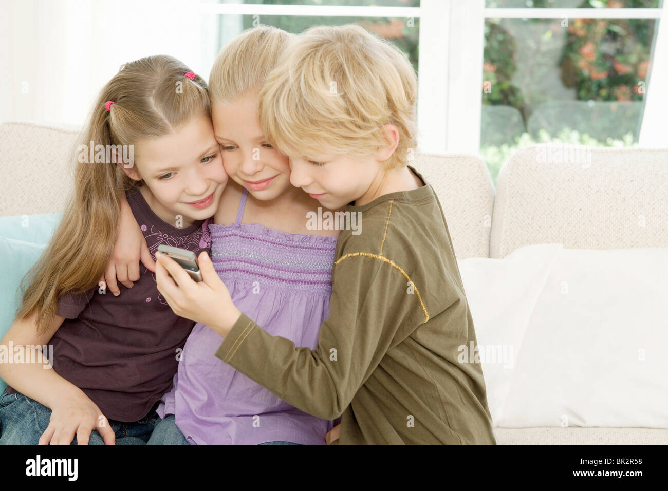 Three children looking at a mobile phone Stock Photo - Alamy