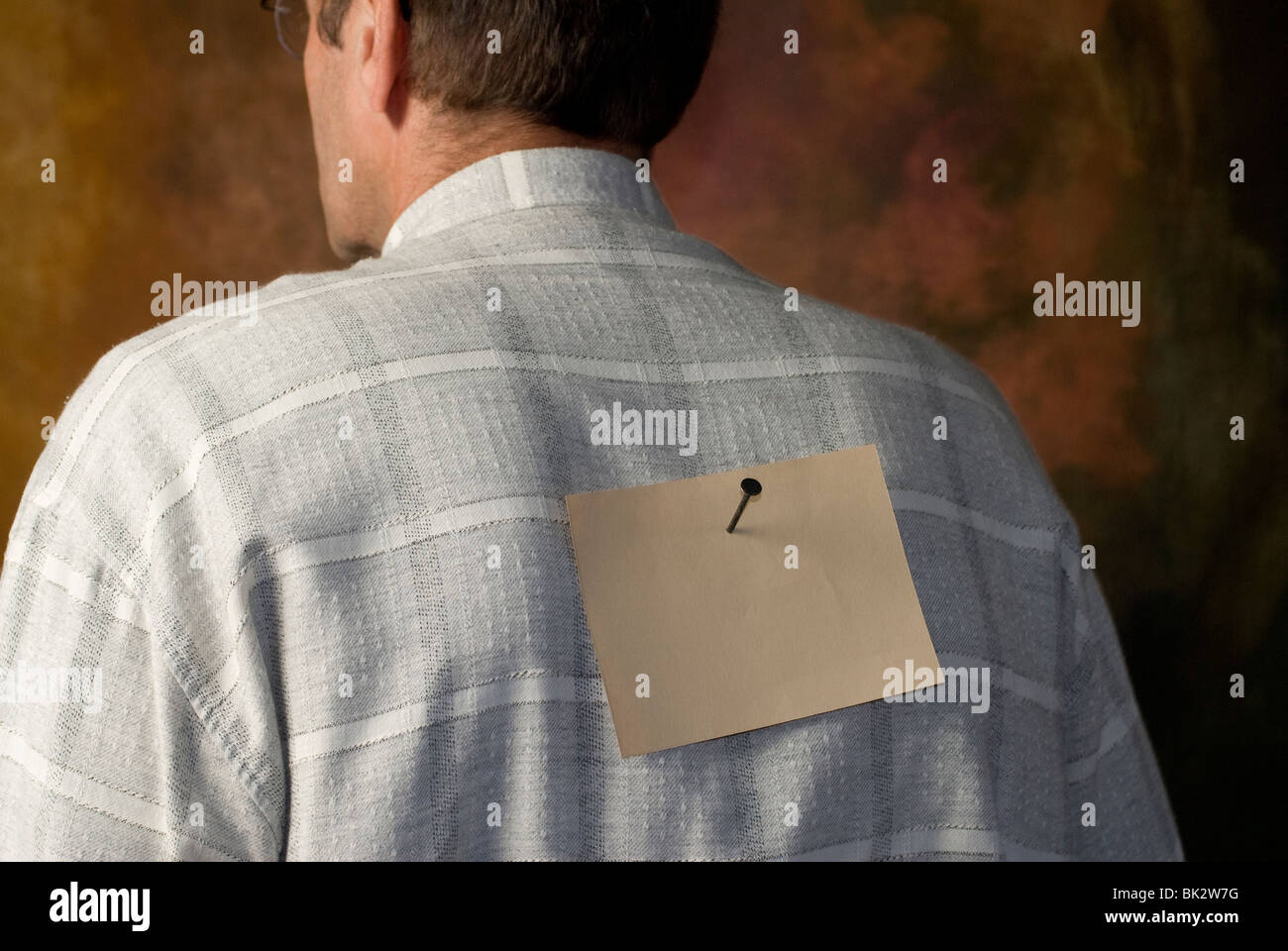 note nailed to man's back Stock Photo - Alamy