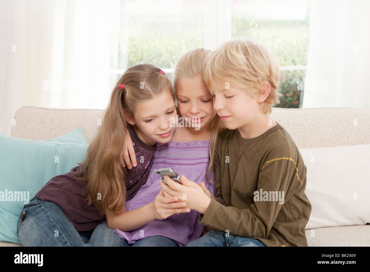 Three children looking at a mobile phone Stock Photo - Alamy