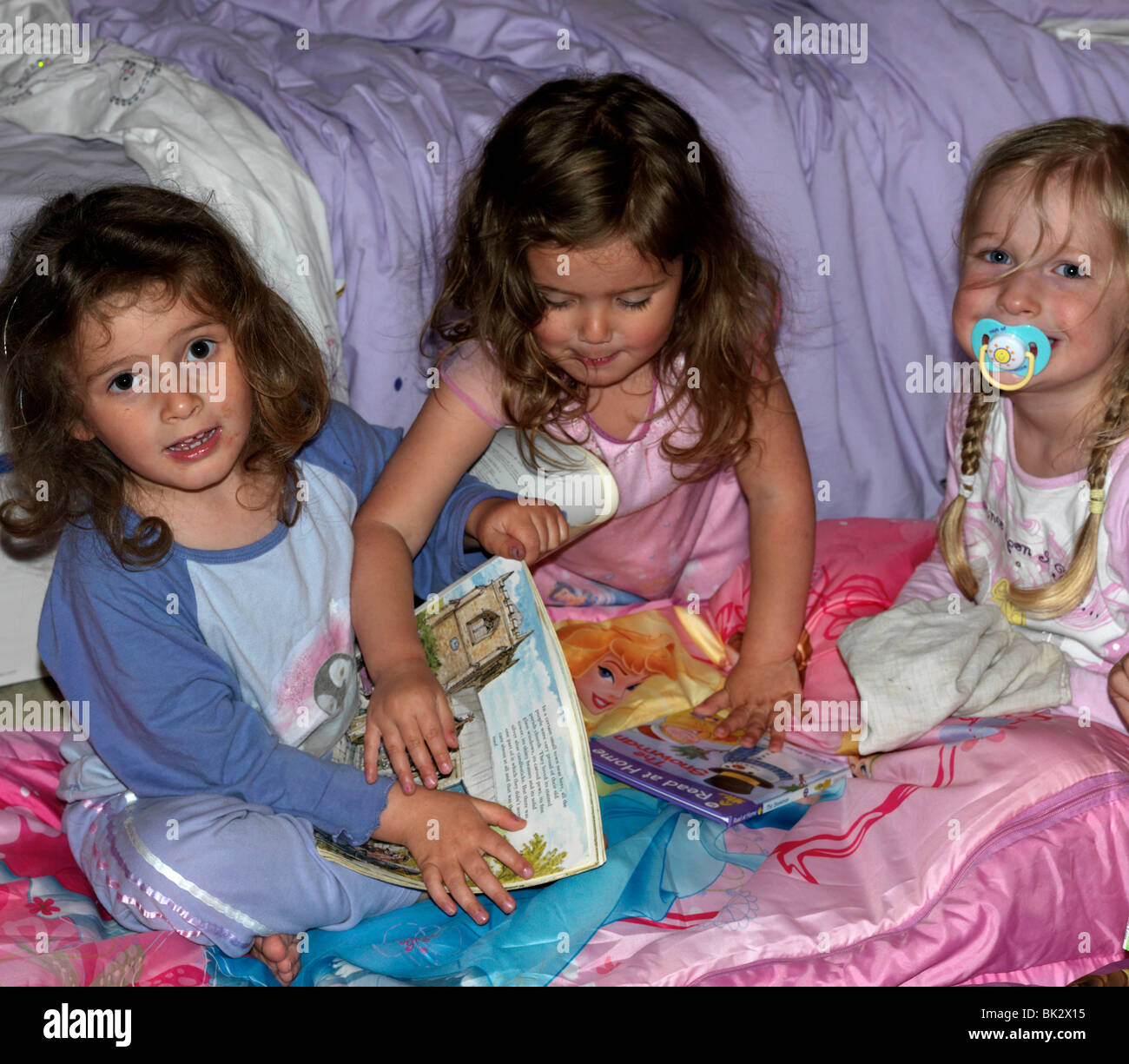 Young Children Having A Sleep Over Reading Books Two Sisters And Cousin ...