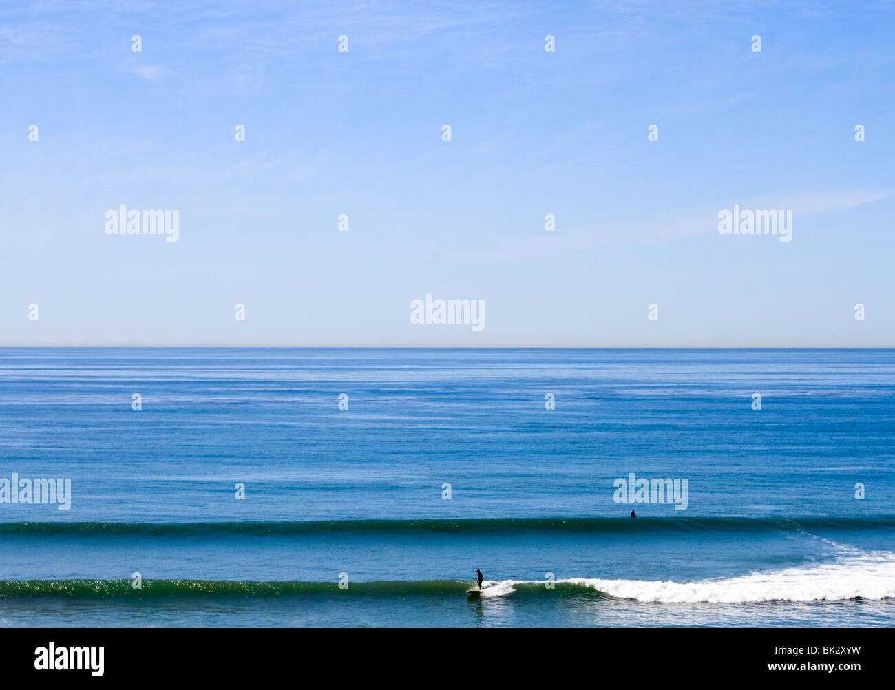 A surfer rides a wave on a sunny blue day at Stone Steps beach in ...