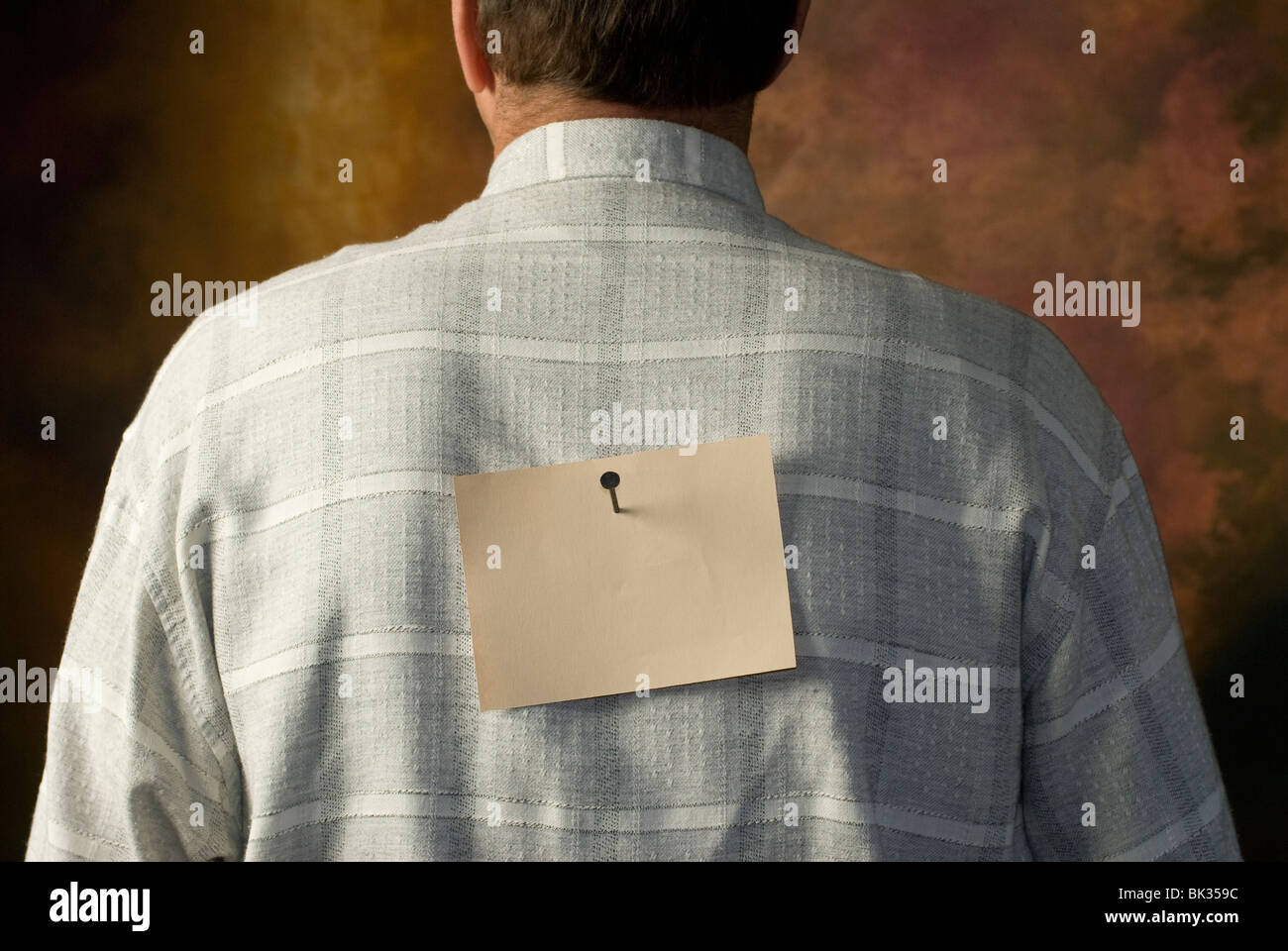 note nailed to man's back Stock Photo - Alamy